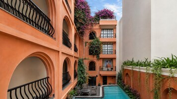 Um pátio com piscina, varandas em arco e vegetação exuberante.