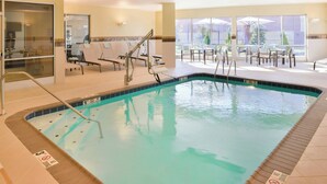 Piscina com placa de proibição de mergulho, cadeiras de espreguiçadeira e área de refeições com guarda-sóis.