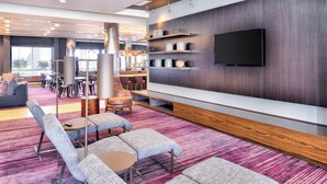 Uma área de estar moderna com assentos, uma TV de tela plana e prateleiras decorativas.
