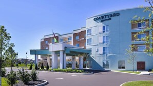Um hotel Courtyard Marriott com design moderno, apresentando uma entrada coberta e vários andares.