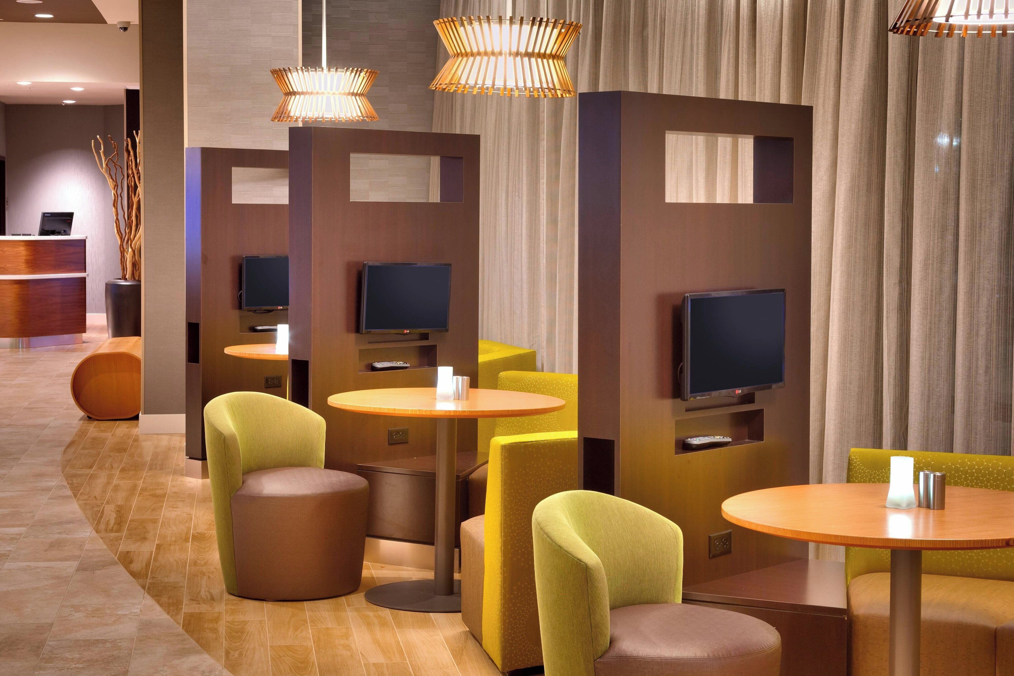 Um hall de hotel moderno com mesas redondas, assentos confortáveis e um balcão de recepção.