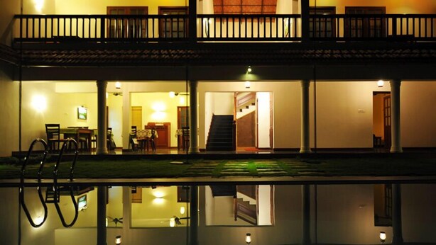 Um edifício de dois andares com varanda, escada e piscina.
