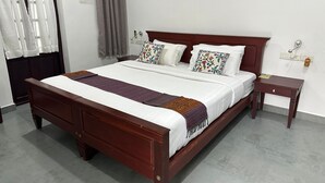 Uma cama bem arrumada com estrutura de madeira, mesa de cabeceira e criado-mudo.