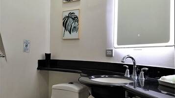 Casa de banho moderna com sanita, bidé e lavatório. Há duas molduras com imagens na parede e uma janela sobre o lavatório.