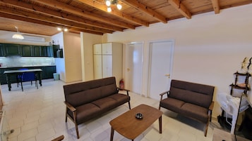 Sala de estar com dois sofás, uma mesa de centro e uma cozinha ao fundo.