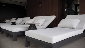 Quarto de hotel moderno com uma cama grande, uma mesa pequena e um sofá.