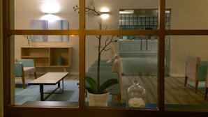 Quarto com uma mesa de madeira, uma planta em vaso e uma cúpula de vidro sobre um pequeno objeto.