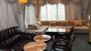 Uma sala de estar com um sofá de couro, uma mesa de centro e uma mesa de jantar com cadeiras.