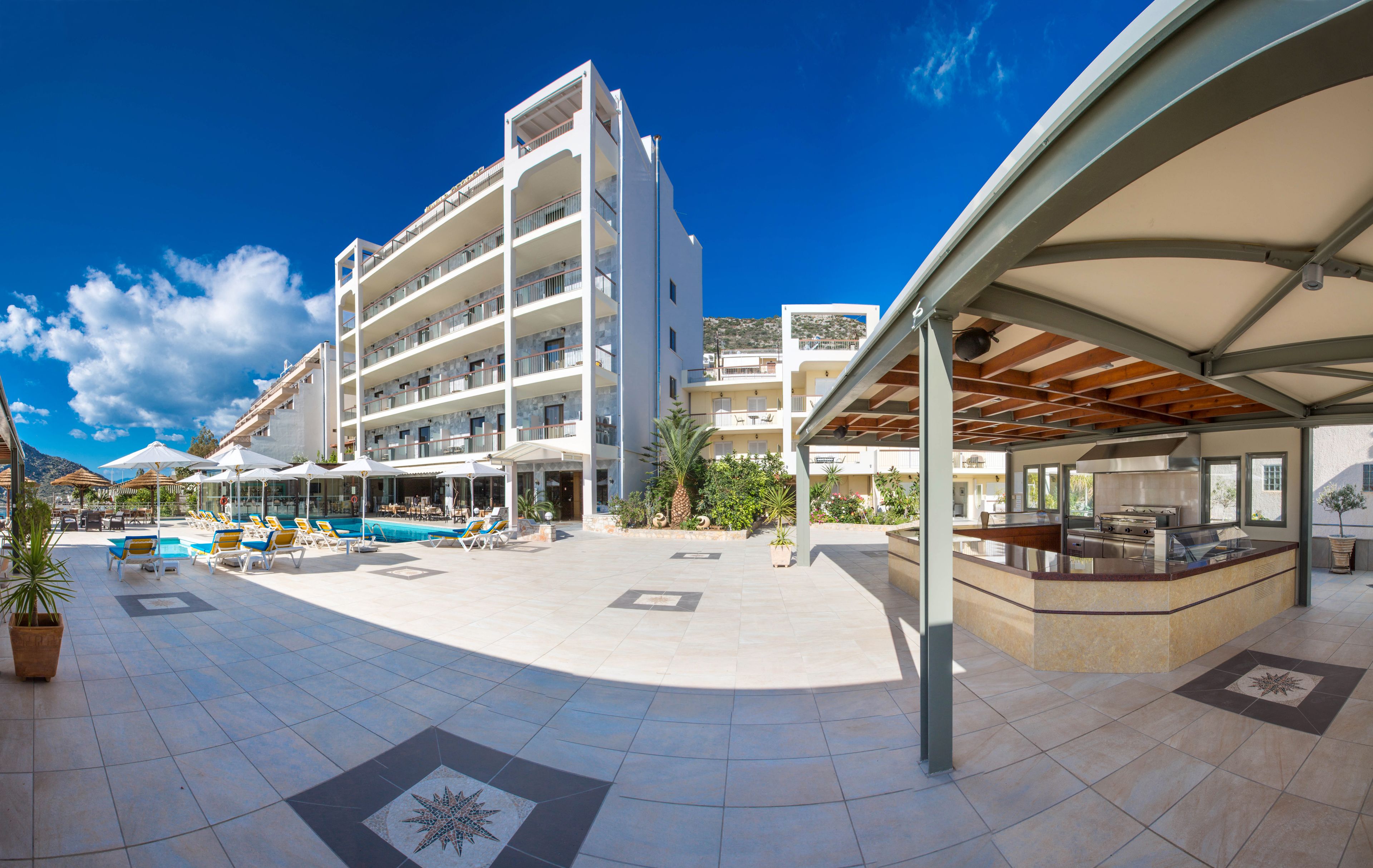 Um hotel com área de piscina, espaço para sentar ao ar livre e área de refeições coberta.