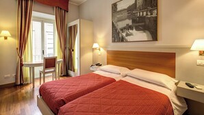 Quarto de hotel com duas camas, uma escrivaninha e uma cadeira.