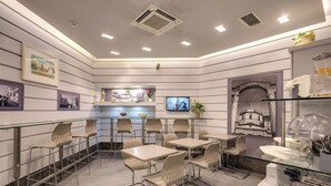 Um restaurante moderno com área de bar, mesas e uma tela de televisão.