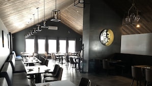 Um restaurante moderno com mesas comunitárias compridas, cabines individuais e teto alto com vigas aparentes.