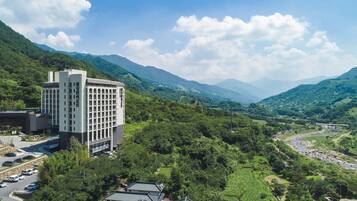 Um hotel moderno com um pátio central, rodeado por vegetação exuberante e montanhas.