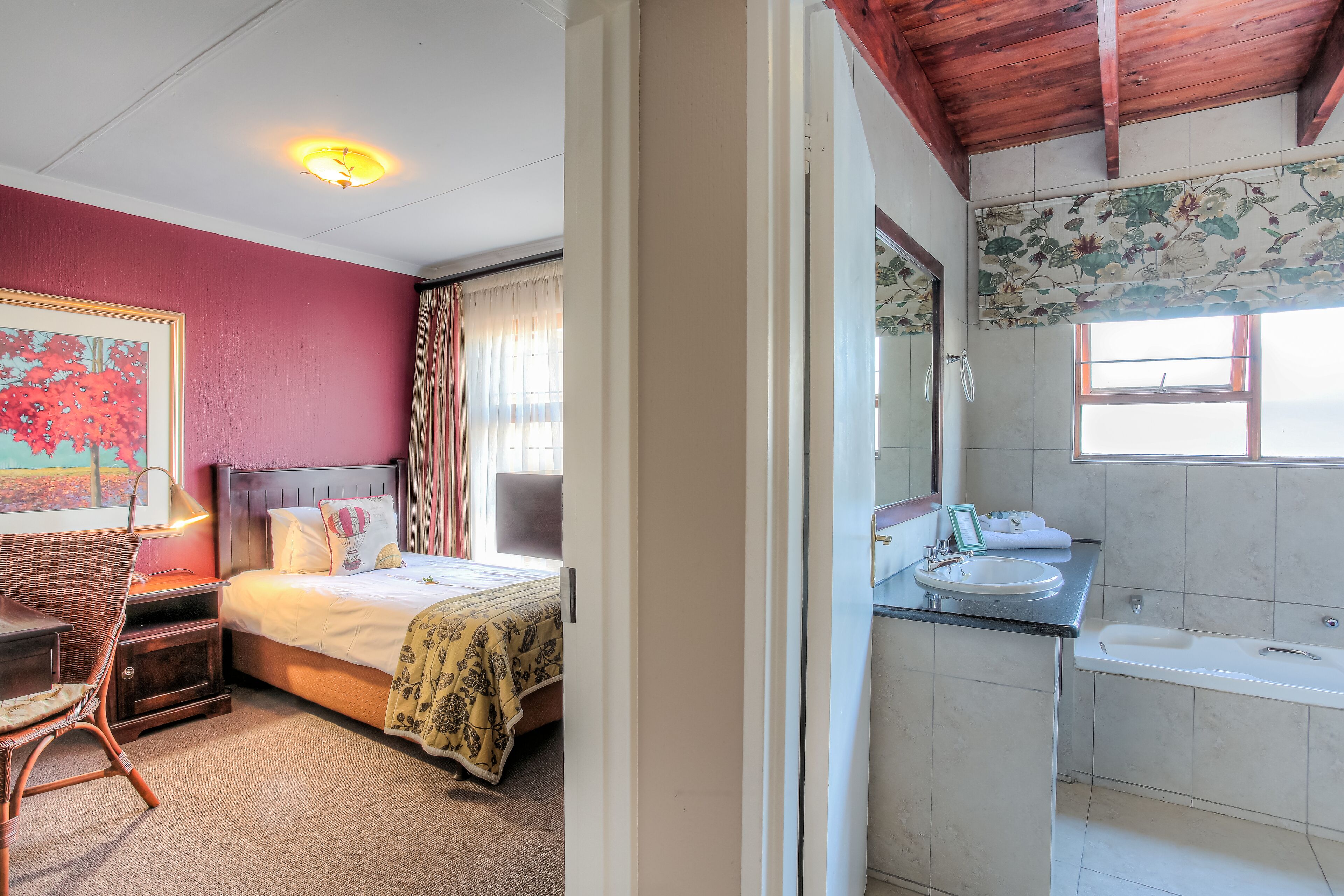 Quarto com cama, mesa de cabeceira e uma cadeira. Inclui banheiro com pia e banheira.