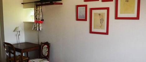 Quarto com uma cama, uma escrivaninha e uma cadeira. Existem quadros na parede.