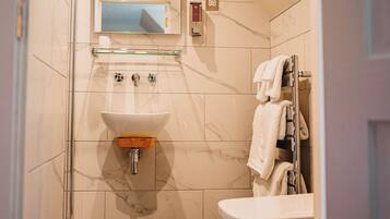 Uma casa de banho pequena e moderna, com uma sanita, uma pia branca e cabine de duche em vidro.