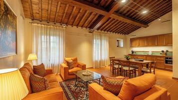 Uma sala de estar ampla com teto de madeira alto, mesa de jantar com cadeiras e cozinha com armários de madeira.