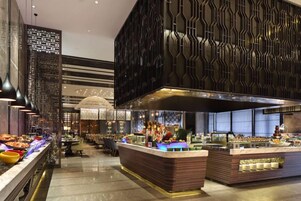 Restaurante moderno com balcão central, diversas opções de assento e parede decorativa com padrão geométrico.