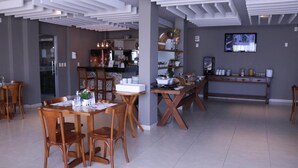 Uma sala de jantar moderna com mobiliário de madeira, cozinha ao fundo e uma televisão de tela plana na parede.