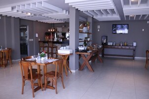 Uma sala de jantar moderna com mobiliário de madeira, cozinha ao fundo e uma televisão de tela plana na parede.