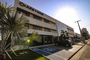 Hotel com fachada moderna, área de estacionamento com acessibilidade para pessoas com deficiência e céu claro.