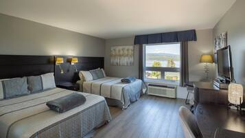 Quarto de hotel com duas camas, uma escrivaninha, televisão e janela com vista para o exterior.