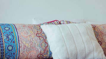 Uma cama com um cobertor colorido e um travesseiro, um quadro de árvore pendurado na parede e um banco em um parque.