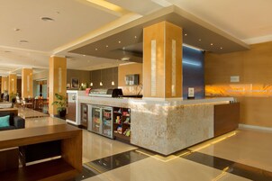 Um hall de hotel moderno com balcão de recepção, área de estar e kitchenette.