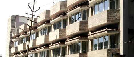 Um edifício de vários andares com uma série de varandas, uma placa com 'Hotel Dominos' e uma placa com 'Nakhchivan Tours and Travels'.