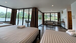 Quarto de hotel moderno com grandes janelas, varanda e vista para um corpo de água.
