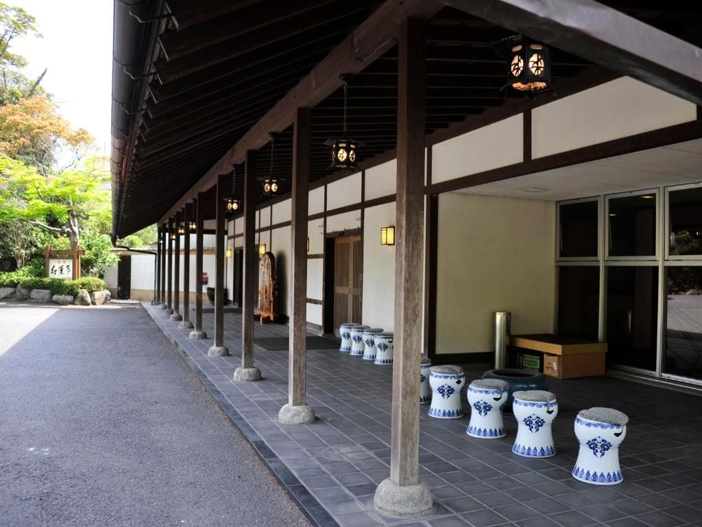 Um edifício japonês tradicional com galeria coberta, lanternas de pedra e estrutura de madeira.