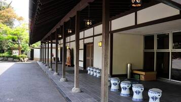 Um edifício japonês tradicional com galeria coberta, lanternas de pedra e estrutura de madeira.