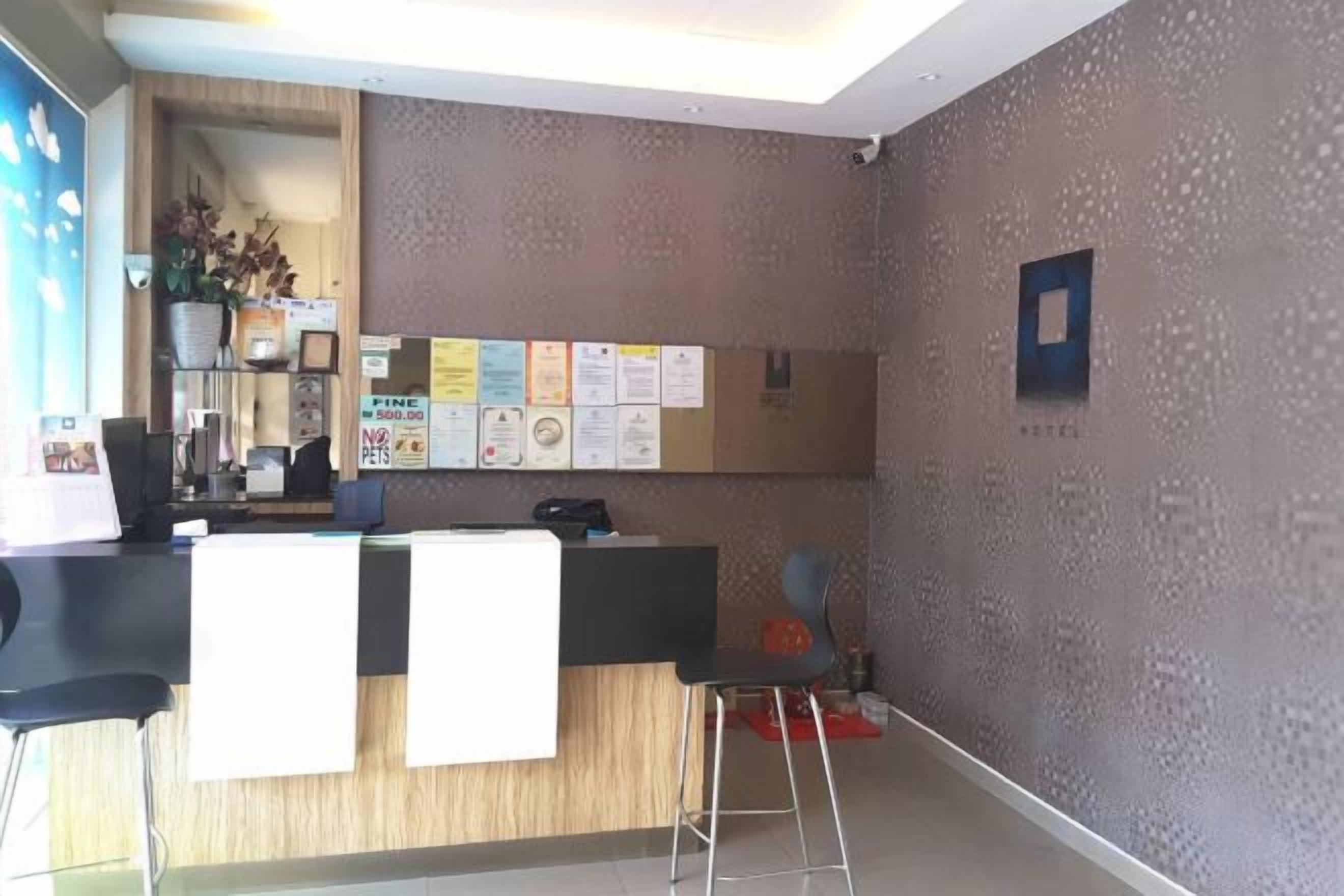 Uma área de recepção com um balcão de madeira, um mural com avisos e parede estampada.
