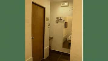 Um corredor estreito com porta, vaso sanitário e espelho.
