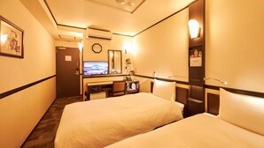 Quarto de hotel com duas camas, uma escrivaninha com computador, televisão e relógio na parede.