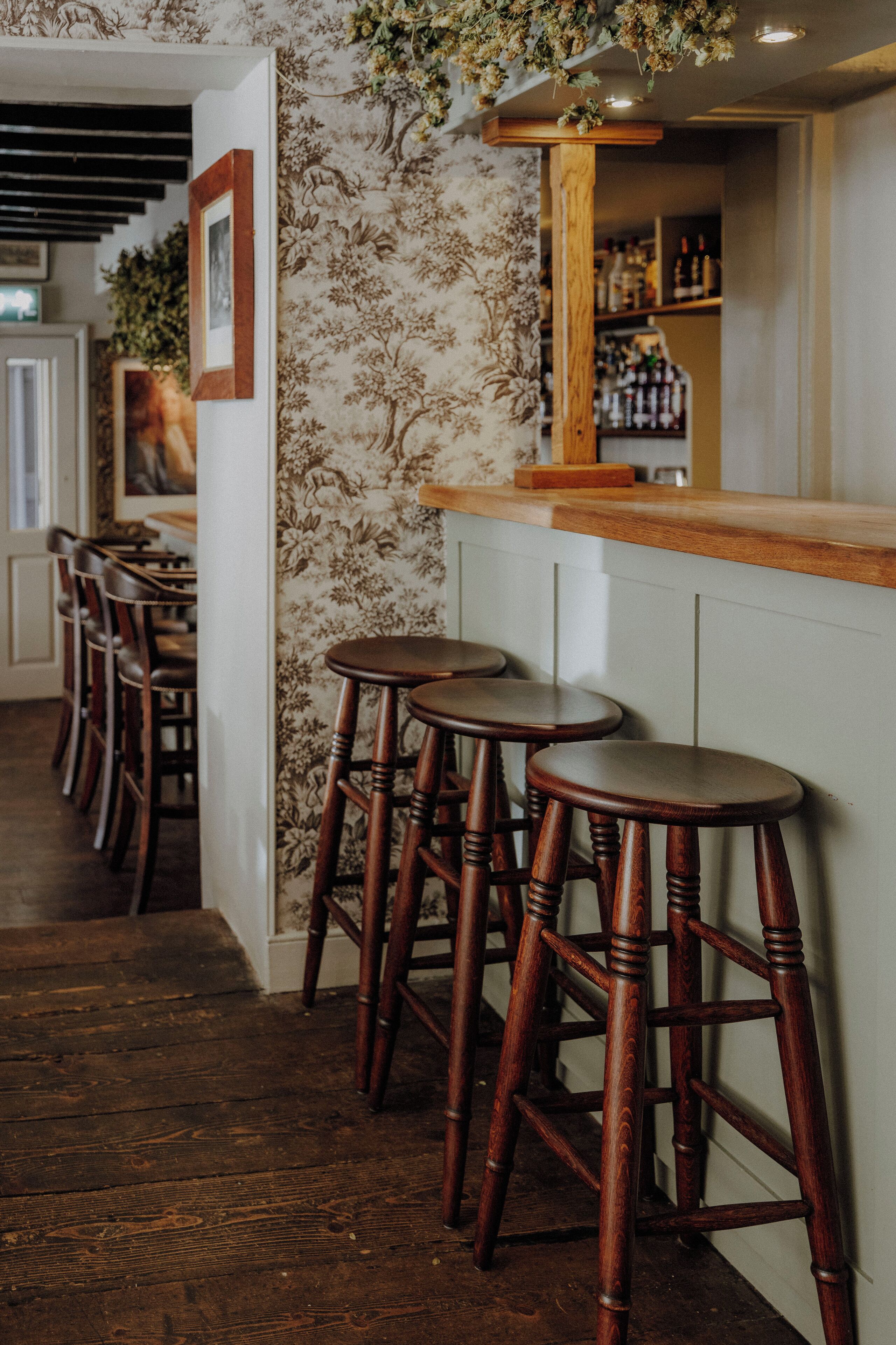 Uma área de bar com banquetas de madeira e balcão.