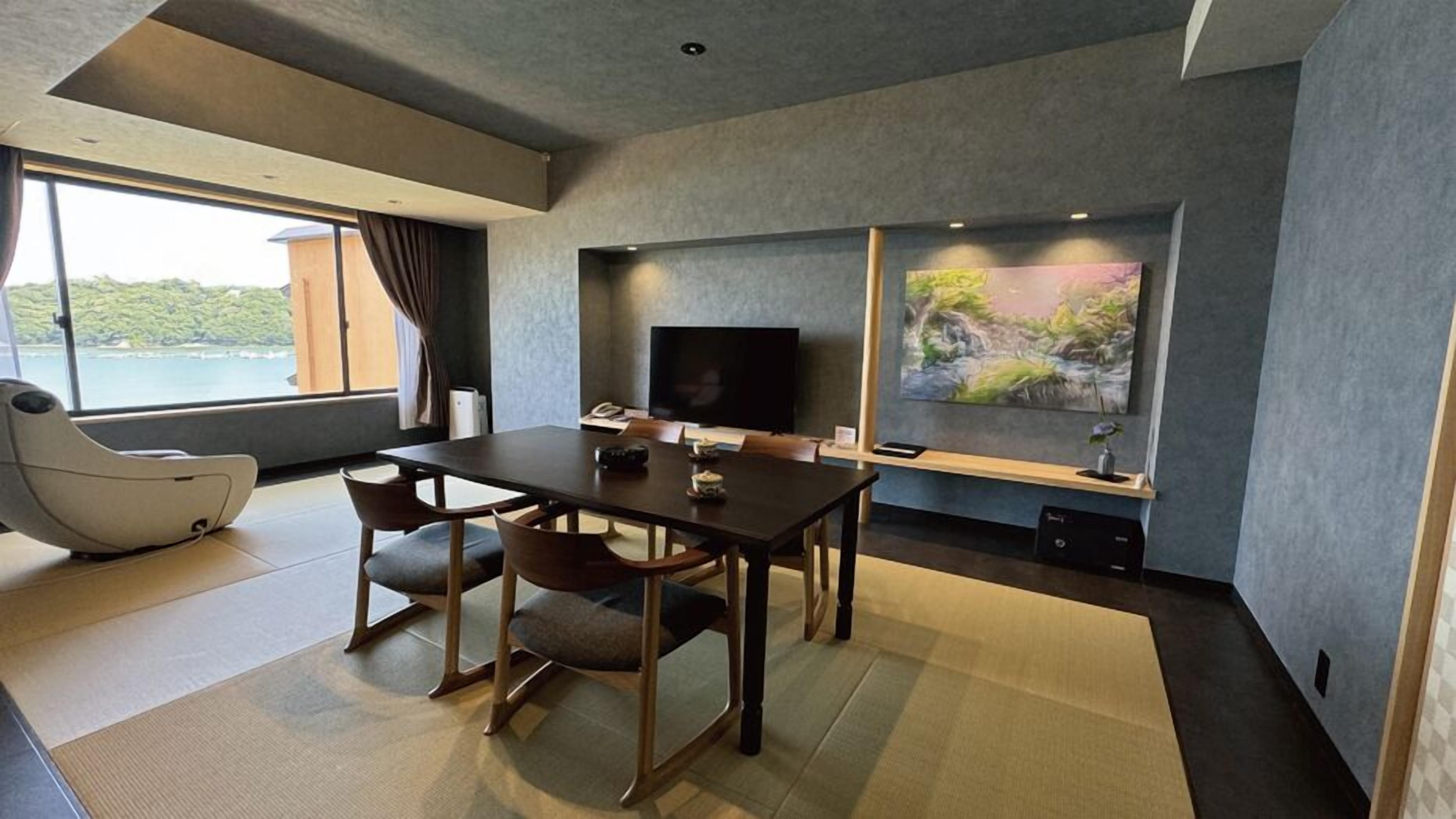 Quarto moderno com mesa de jantar, cadeiras, TV de tela plana, um quadro e vista para o exterior.
