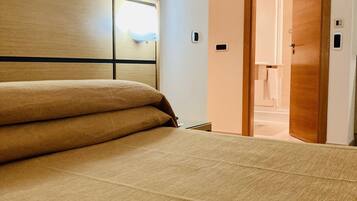 Quarto de hotel com uma cama grande, cabeceira de madeira, mesa de cabeceira e porta para um banheiro.