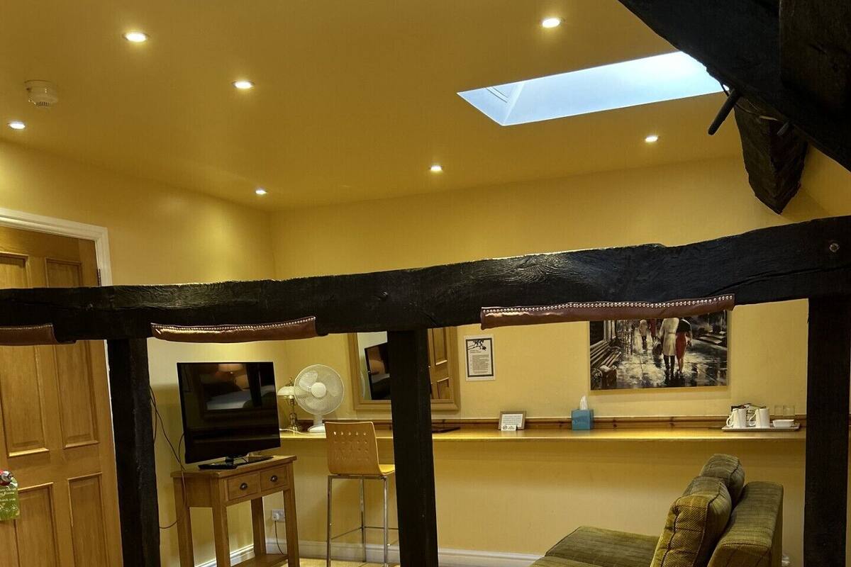 Quarto com cama, televisão, escrivaninha e cadeira.