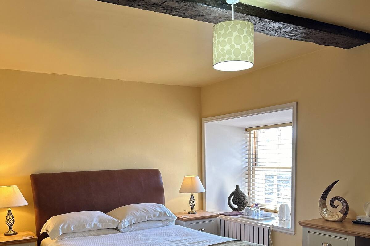 Um quarto bem arrumado com uma cama grande, mesas de cabeceira, uma escrivaninha e uma cadeira.