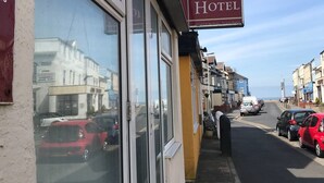 Um hotel com vista clara para a rua e carros estacionados na frente.