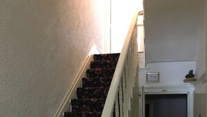 Uma escadaria com degraus revestidos de carpete floral e um corrimão branco.