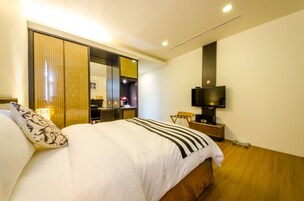 Quarto de hotel com cama, televisão, guarda-roupa e espelho.