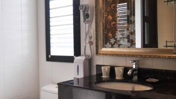 Um polibã e uma banheira separados, um secador de cabelo, chinelos