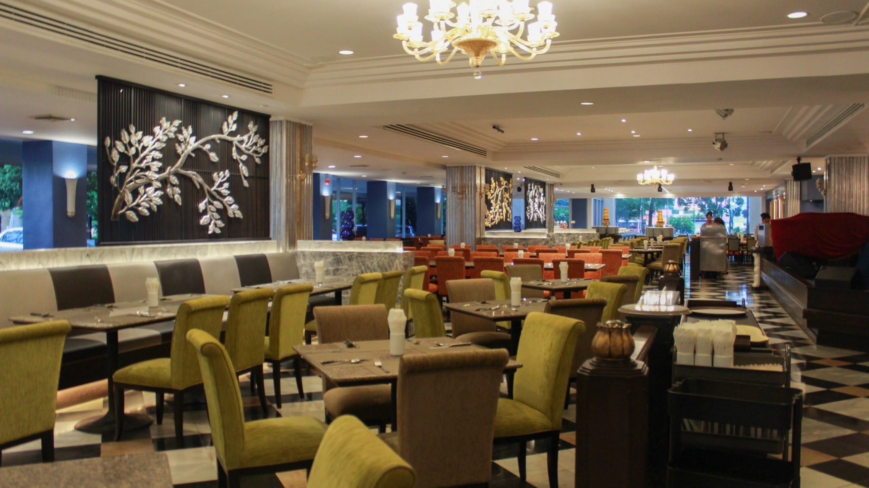 Restaurante com cabines e mesas, um candelabro e vista para o exterior.
