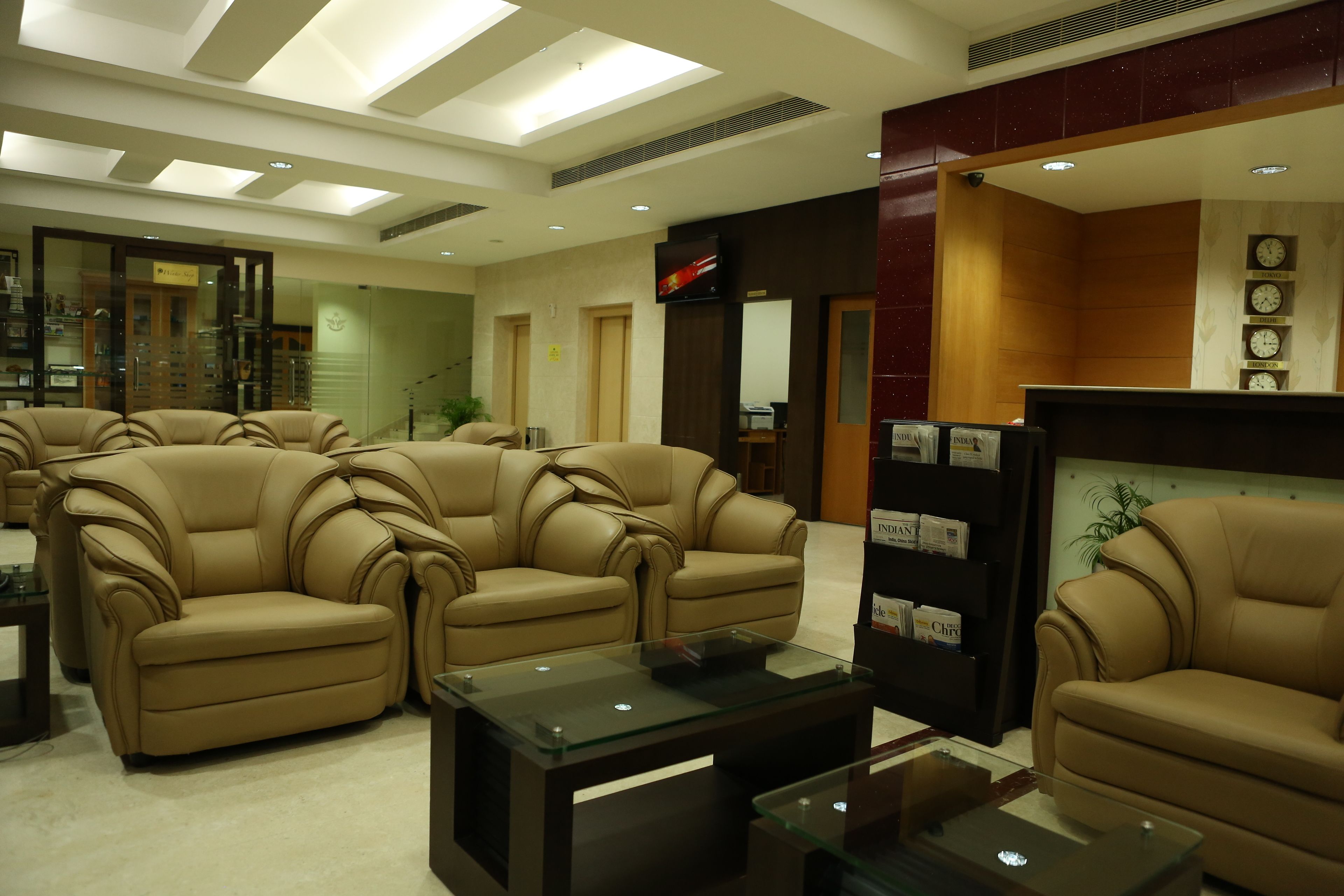 Um hall com vários sofás de couro, um balcão de recepção e um relógio de parede.