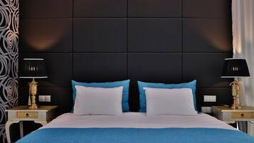 Quarto de hotel com uma cama grande, duas mesas de cabeceira e cabeceira preta.