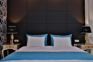 Quarto de hotel com uma cama grande, duas mesas de cabeceira e cabeceira preta.