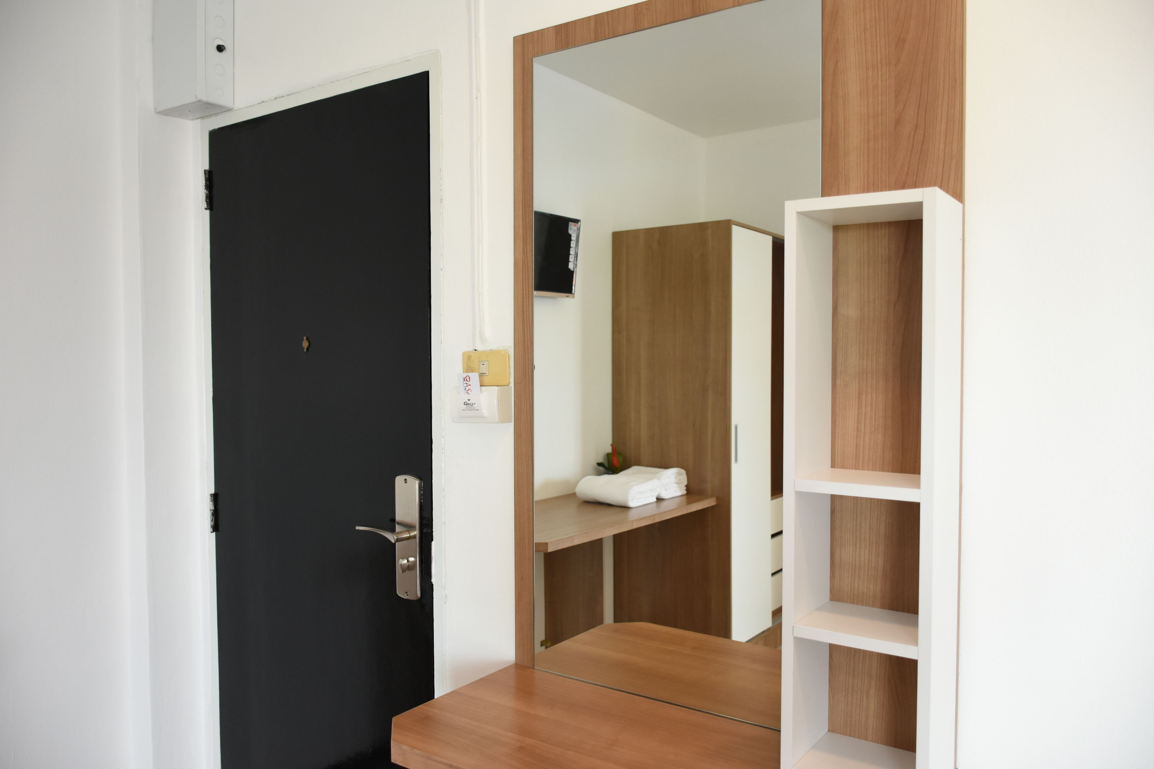 Uma casa de banho moderna com porta preta, prateleiras de madeira e um espelho.