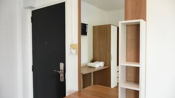 Uma casa de banho moderna com porta preta, prateleiras de madeira e um espelho.